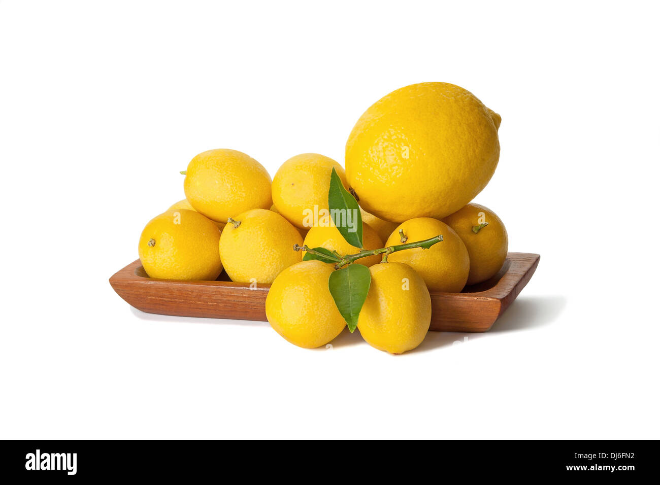 Large and small lemons in a wooden plate isolated on white background ...