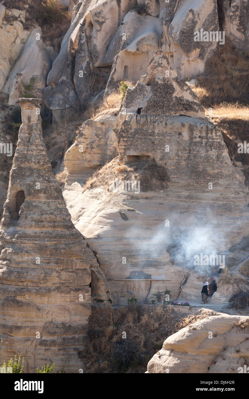 A woman tends her oven near her Cave Dwelling . Smoke rises from a ...
