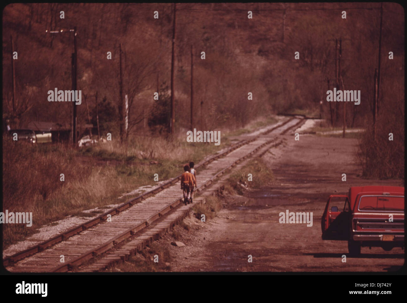 YOUNGSTERS WALK ON TIES OF THE RAILROAD TRACKS THAT PASS THROUGH FIRECO ...