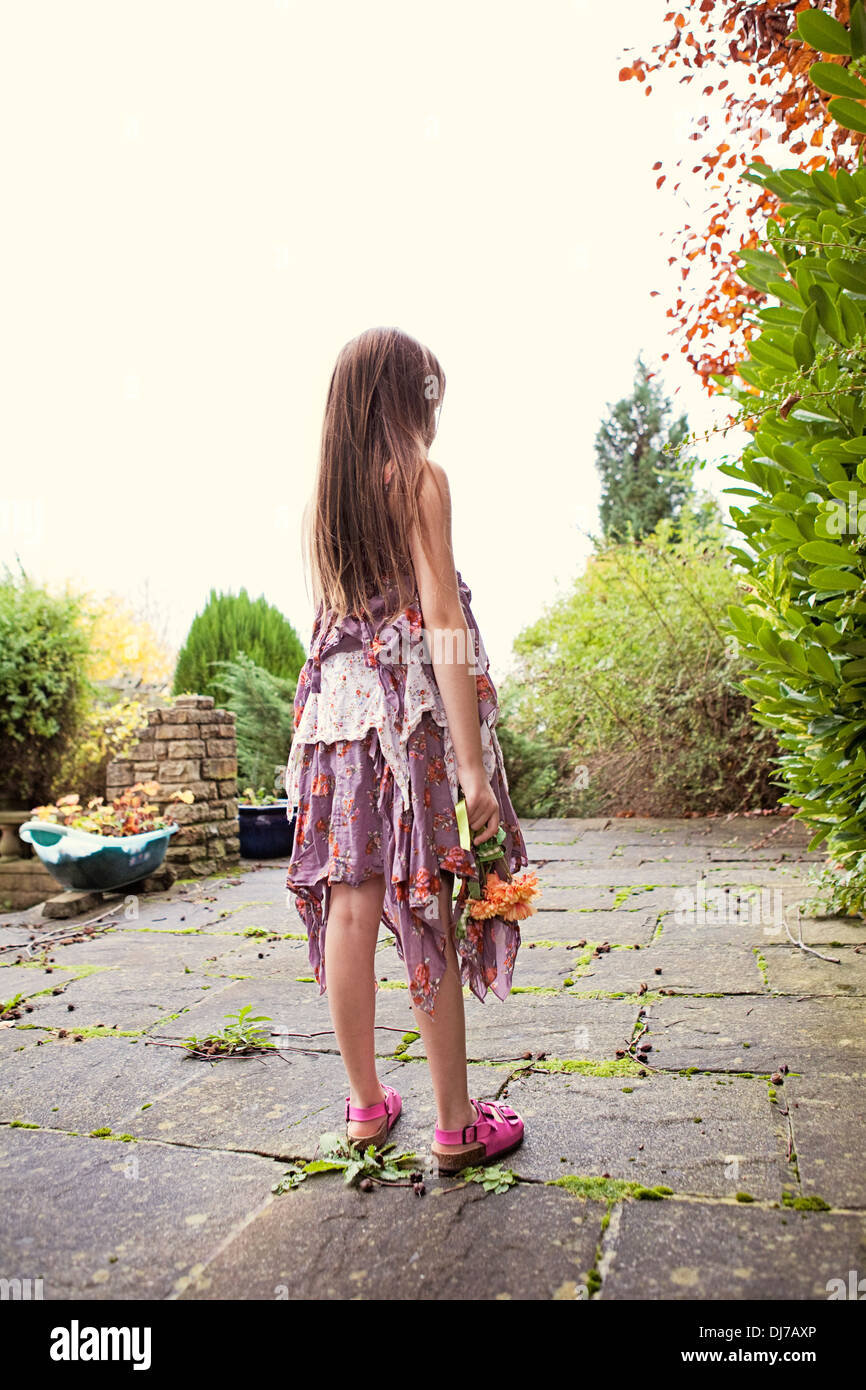 Girl outdoors in ragged dress, looking away from the camera on a summer ...