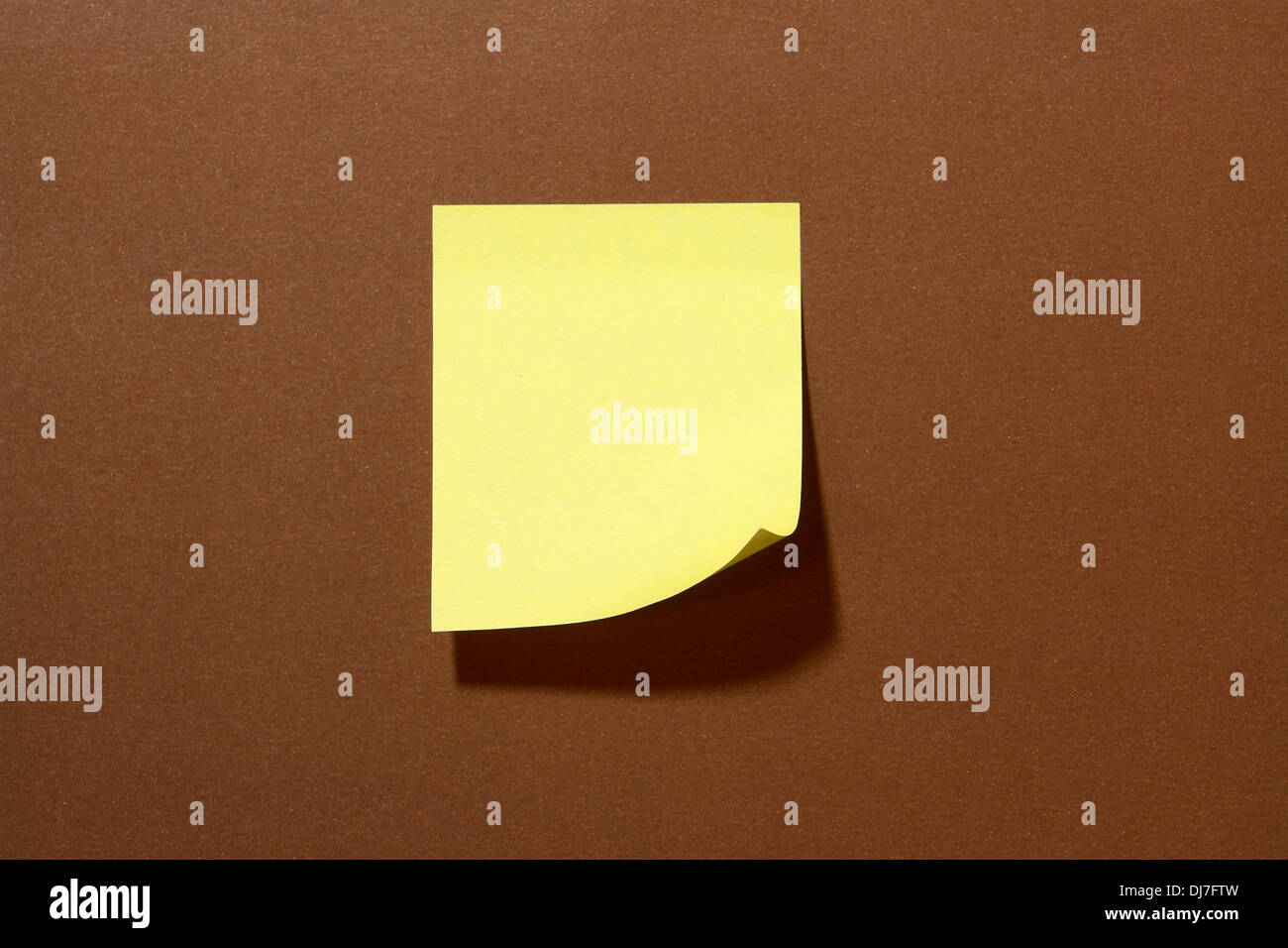 Single curled yellow Post-it on brown background Stock Photo - Alamy