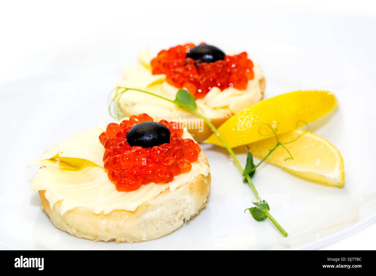 canape with red caviar and lemon on white background Stock Photo - Alamy