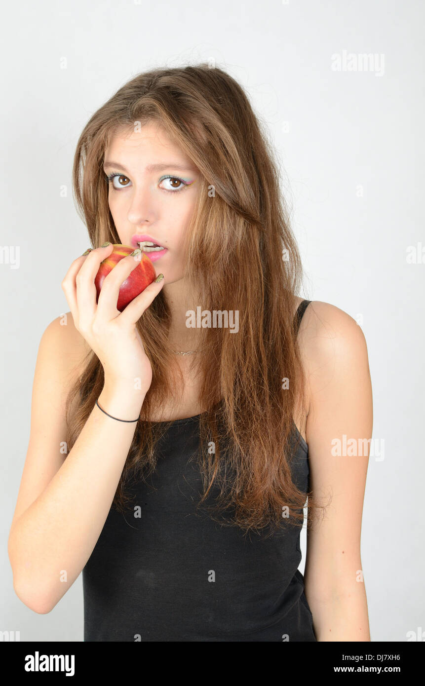 Portrait of young female model eating apple. Girl holding in hand fruit ...