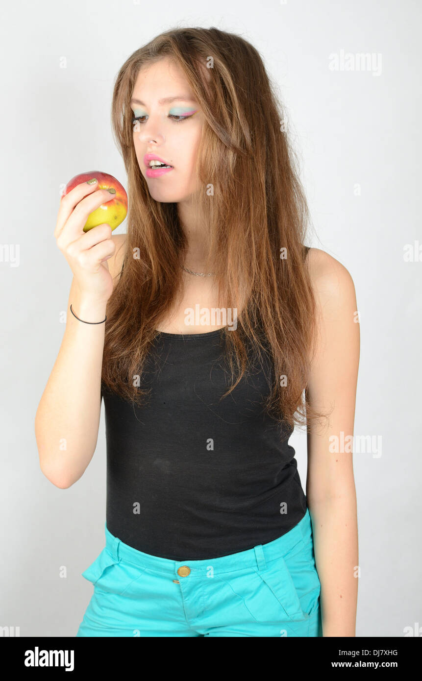 Portrait of young female model eating apple. Girl holding in hand fruit ...