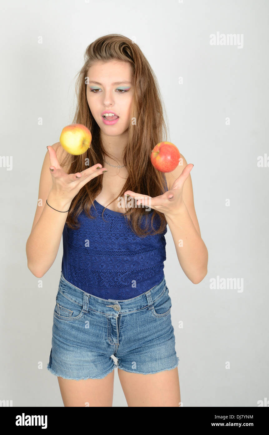Young female model is throwing two apples up in the air. Pretty girl ...