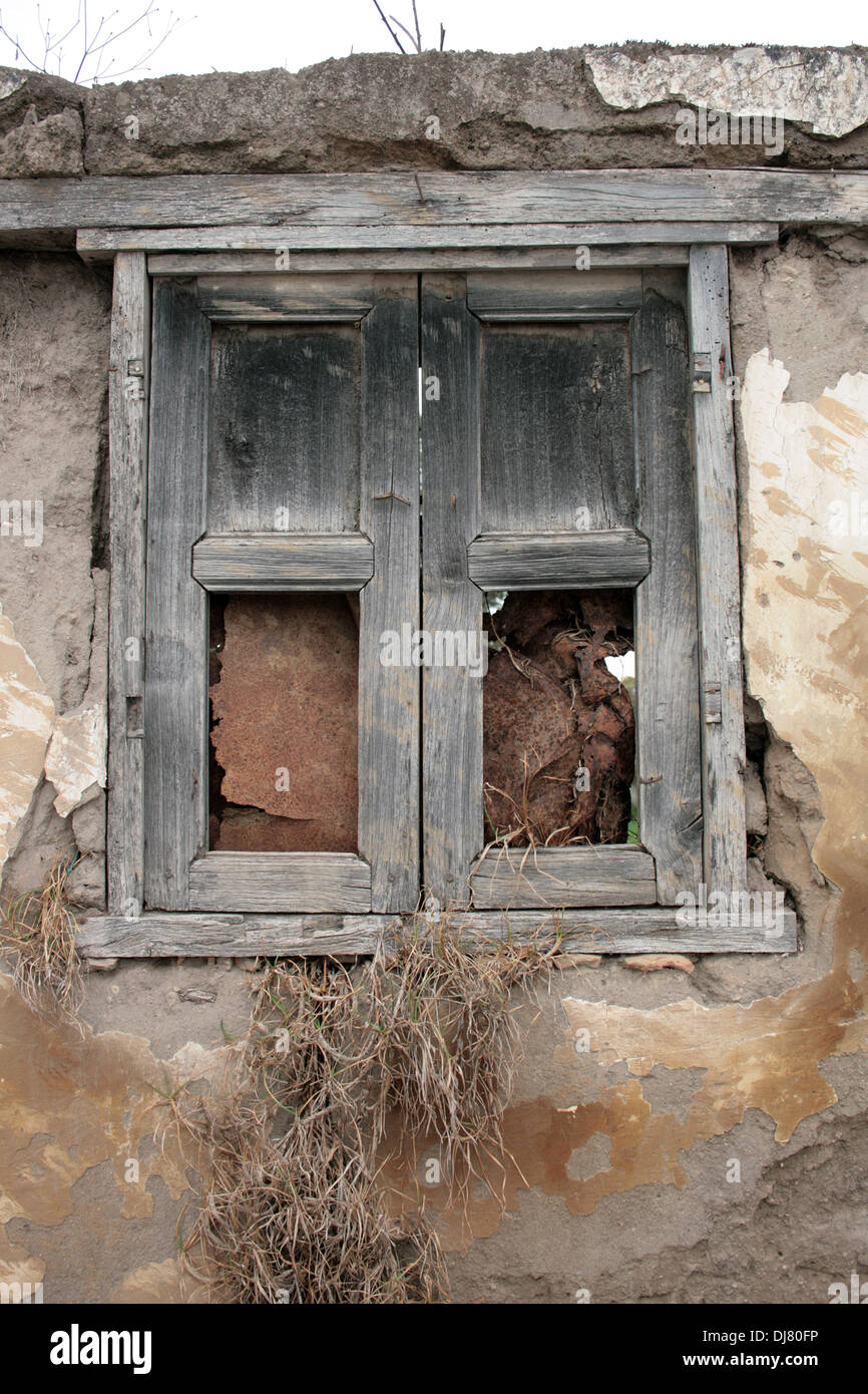 A weathered gray wooden window set in the wall of a demolished building ...
