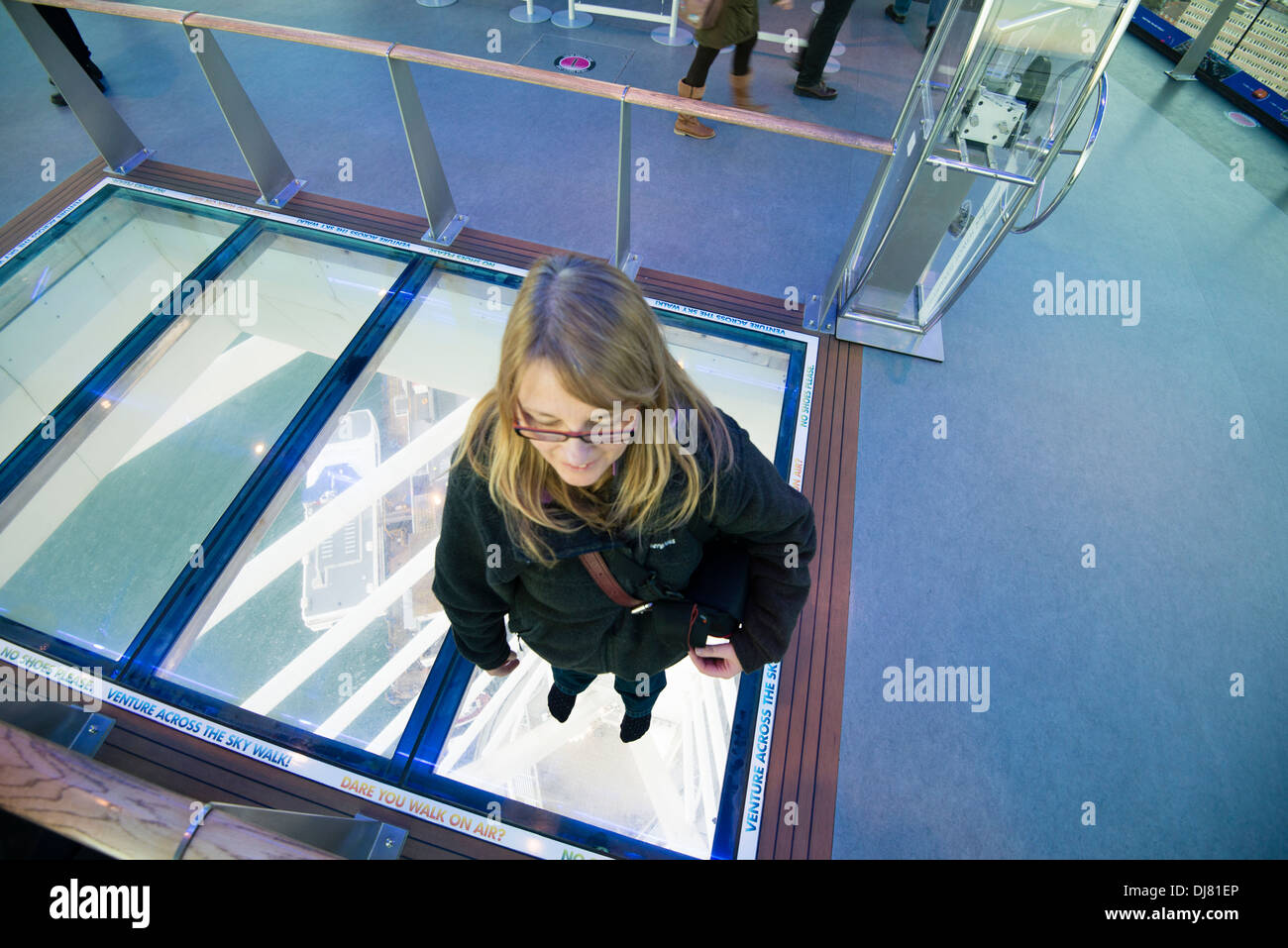 A woman stands on the glass viewing floor of the Spinnaker tower ...