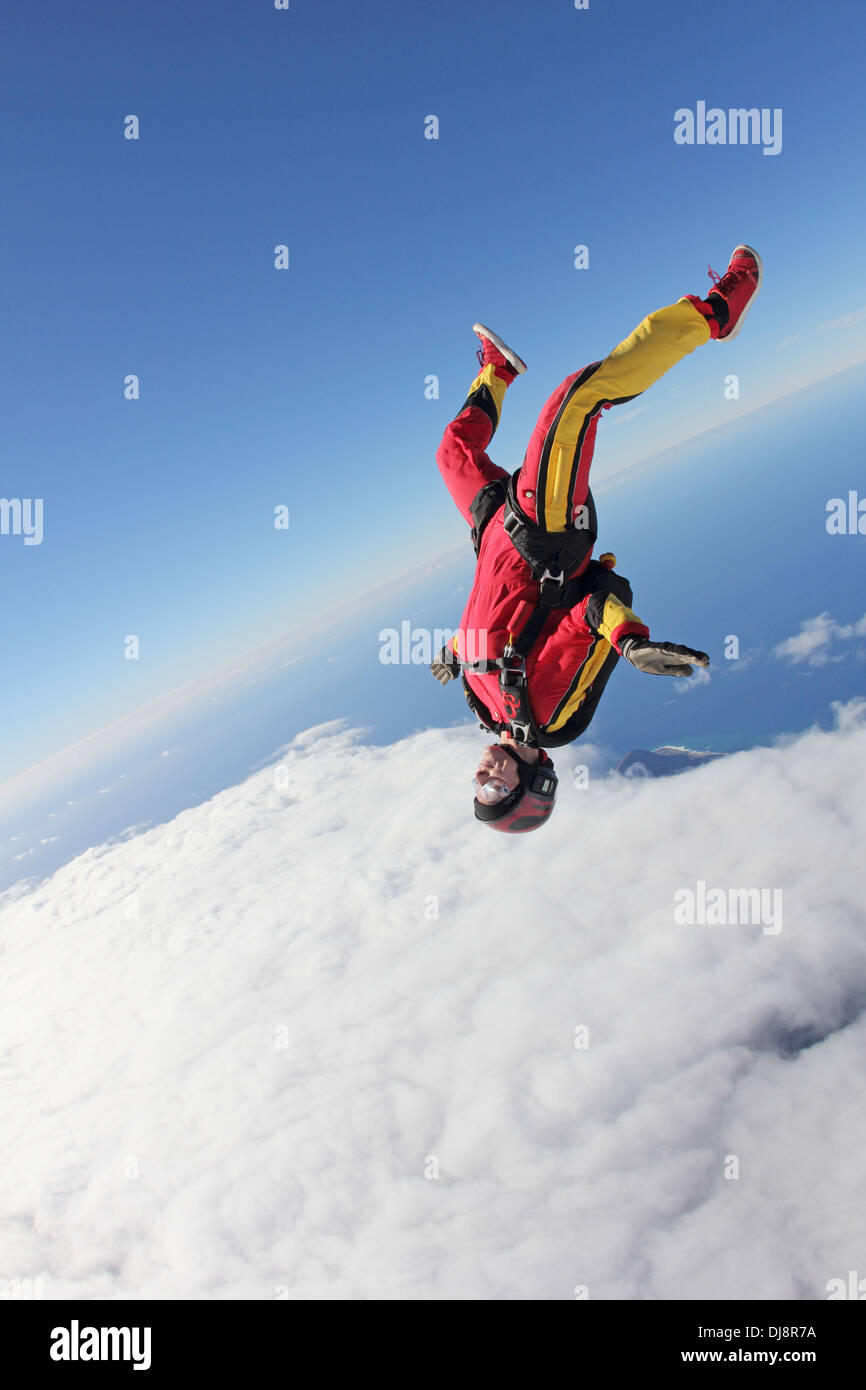 This skydiver woman is falling free in a head down position over a big ...