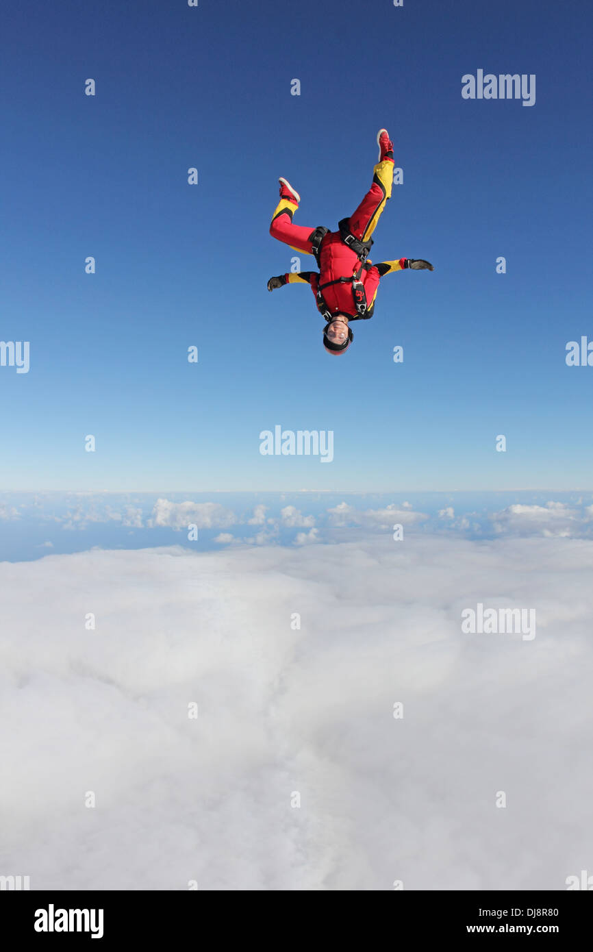 This skydiver woman is falling free in a head down position over a big ...