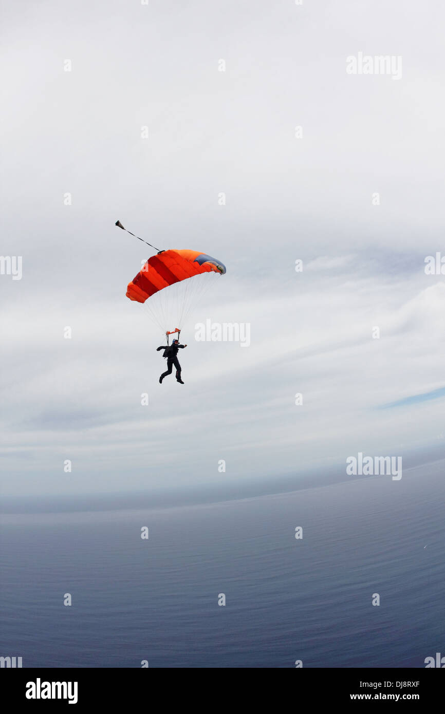 Skydiver under canopy is flying high in the sky under clouds into ...