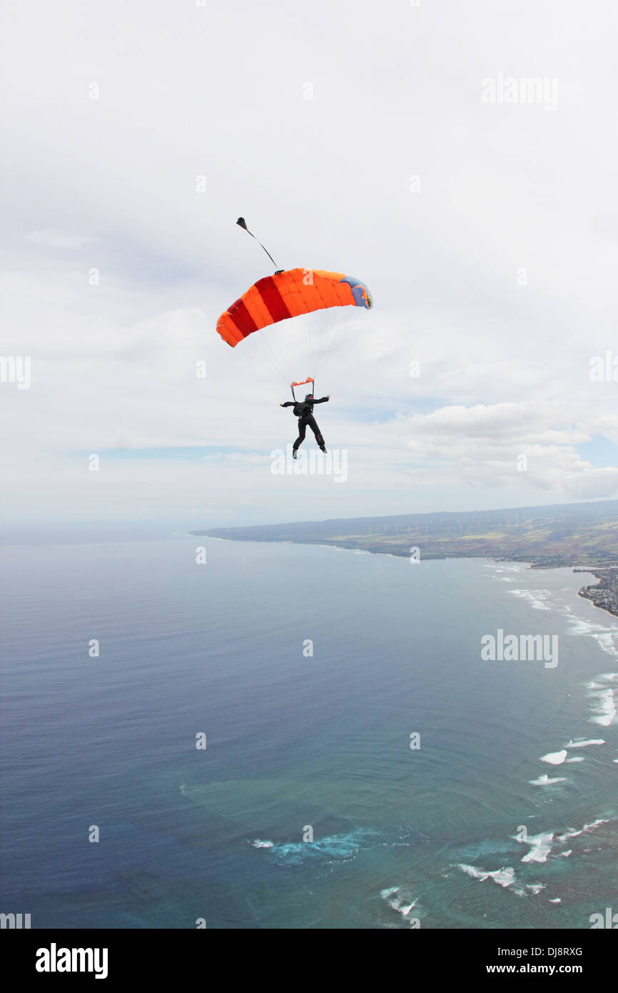 Skydiver under canopy is flying high in the sky under clouds into ...