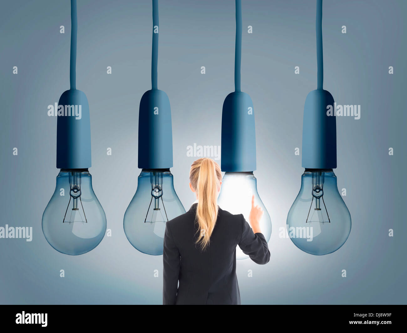 Blonde businesswoman pointing at huge light bulb Stock Photo - Alamy
