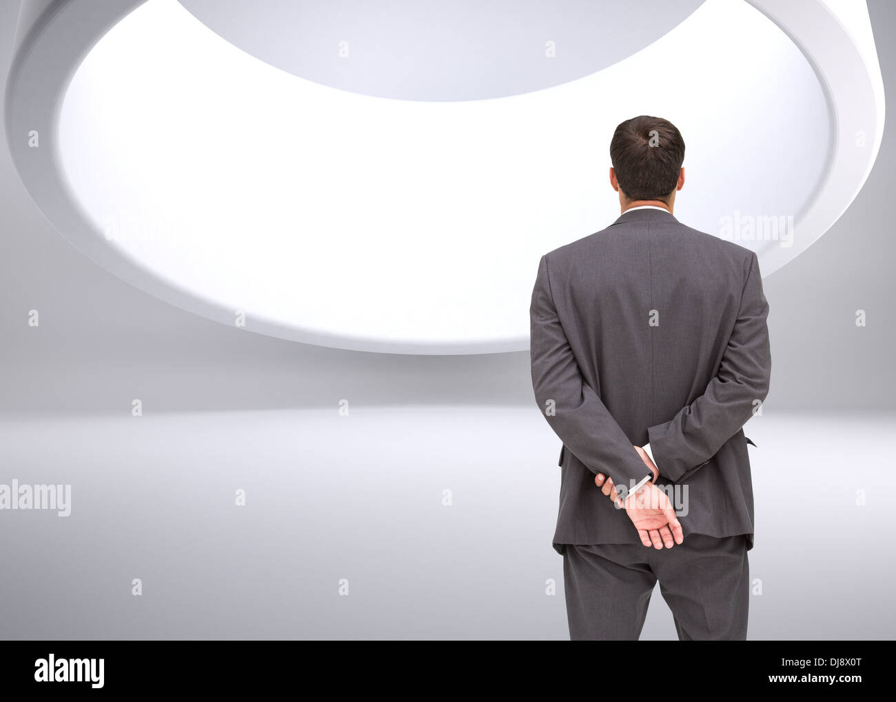 Businessman standing with hands behind back Stock Photo - Alamy