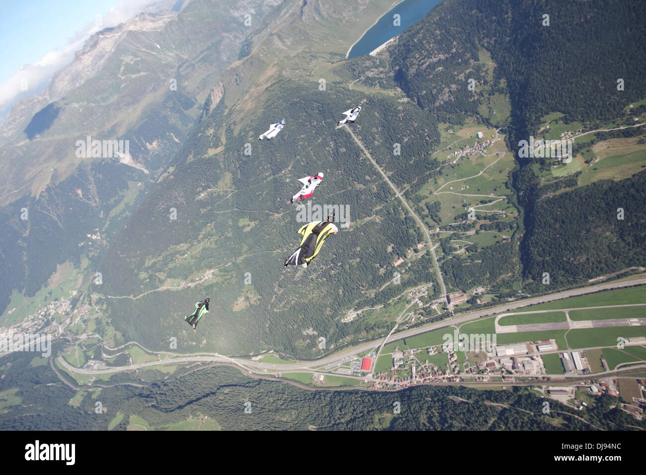 Wingsuit skydivers are flying together in an arrow formation over a ...