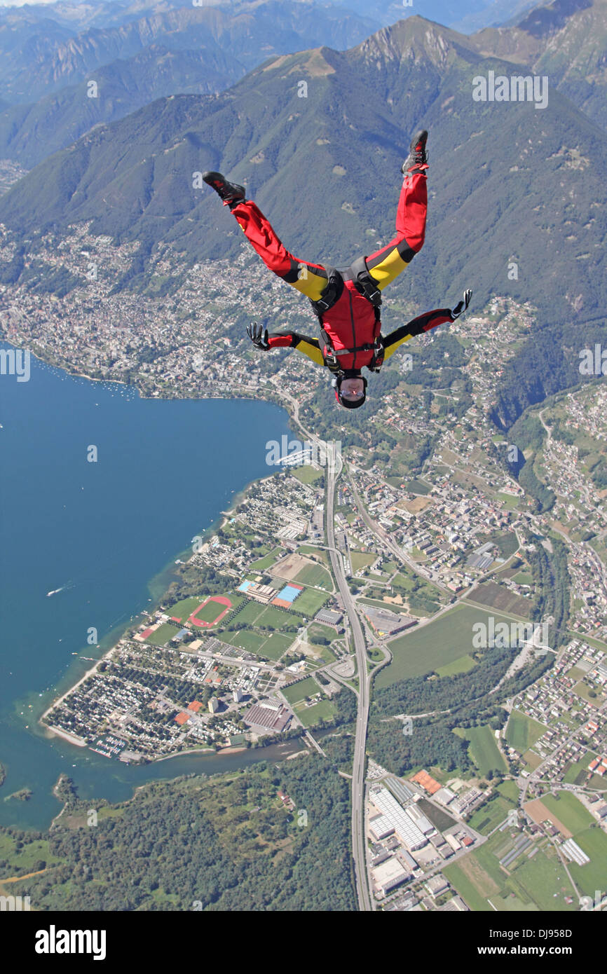 This skydiver woman is falling free in a head down position over a city ...