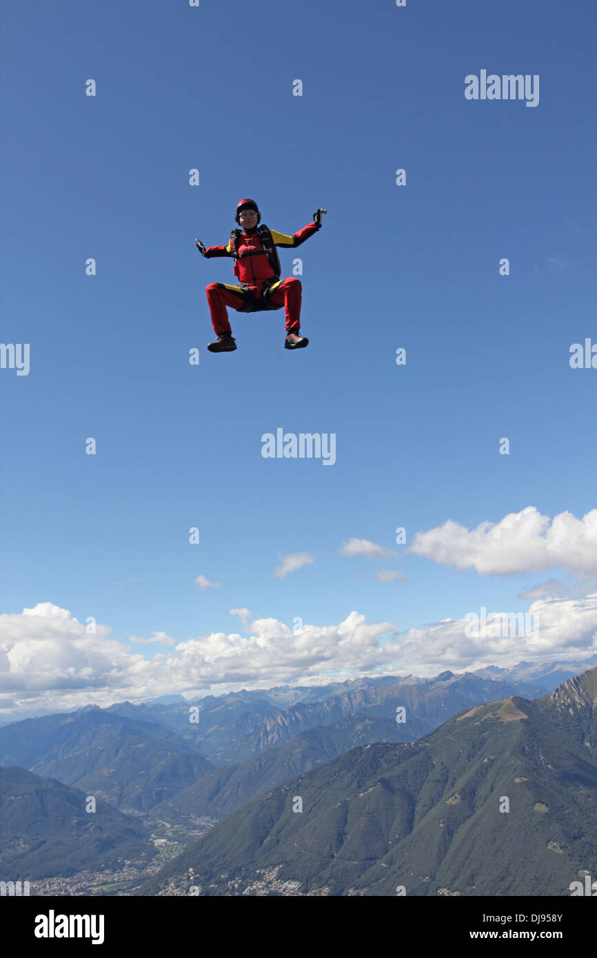This skydiver woman is falling free in a sit position over a big lake ...