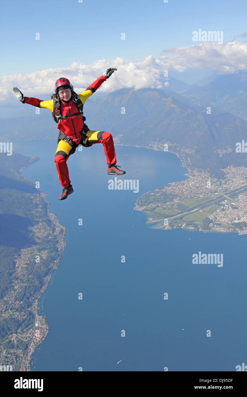 This skydiver woman is falling free in a sit position over a big lake ...
