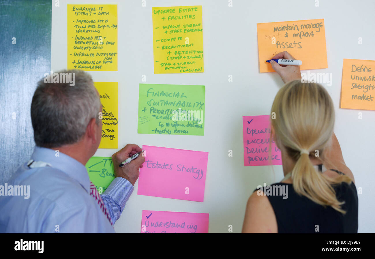Two people writing ideas on post-it notes during a brainstorming Stock ...