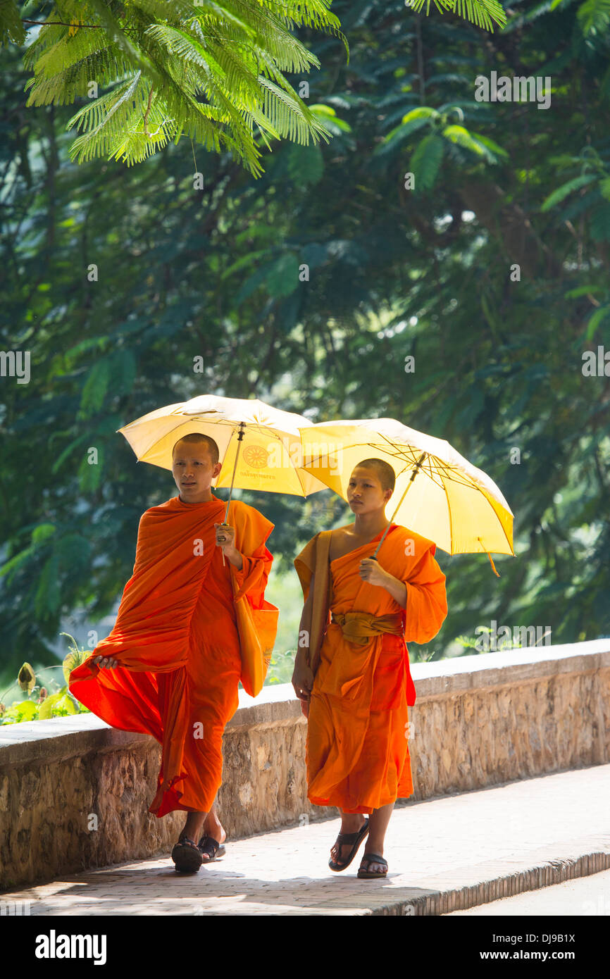 Young novice monks walk along the bank of the Nam Khan river in Luang ...