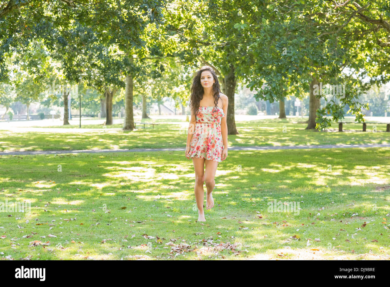 Stylish happy brunette walking on grass Stock Photo - Alamy