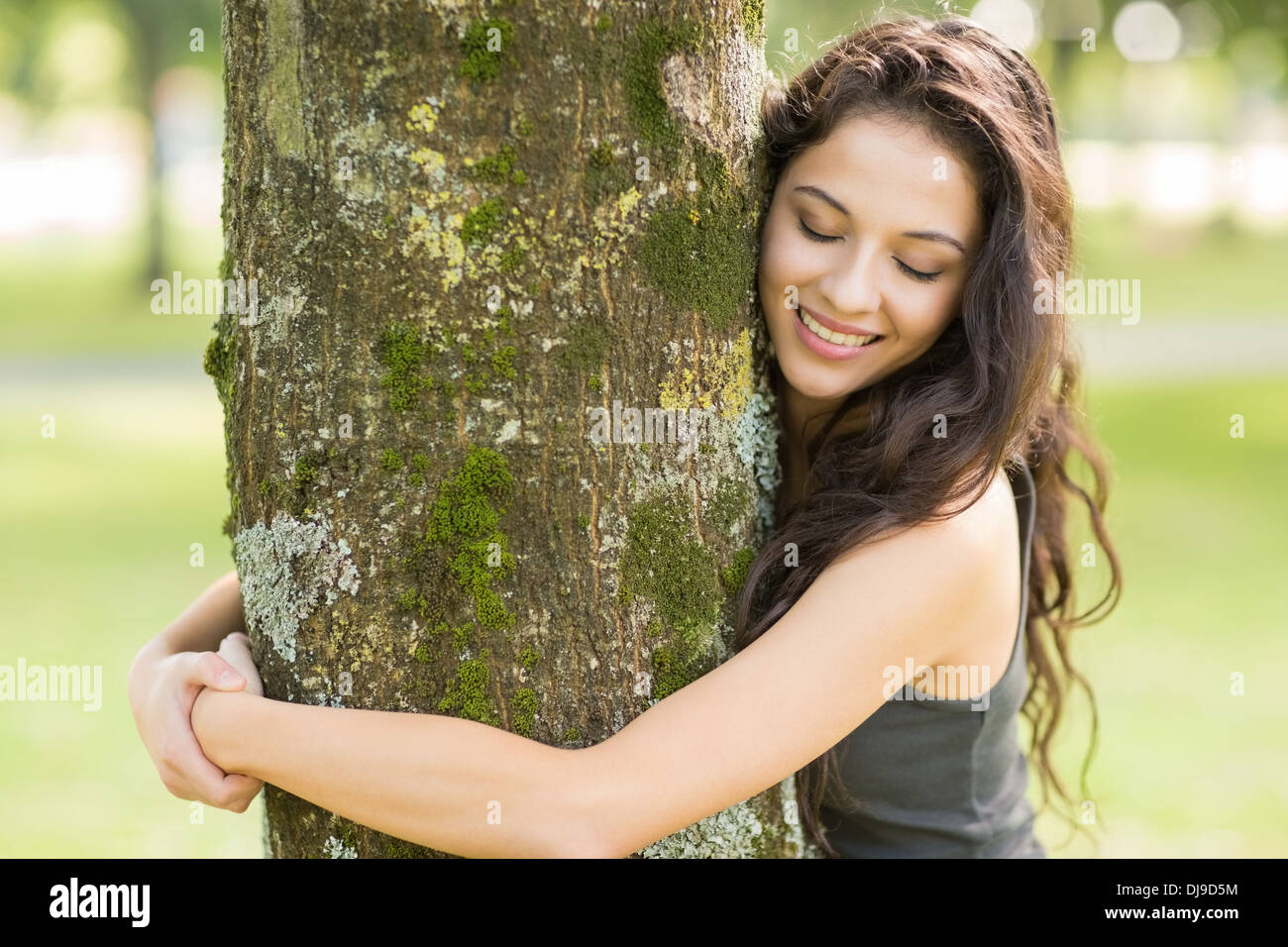 Casual cheerful brunette embracing a tree with closed eyes Stock Photo ...