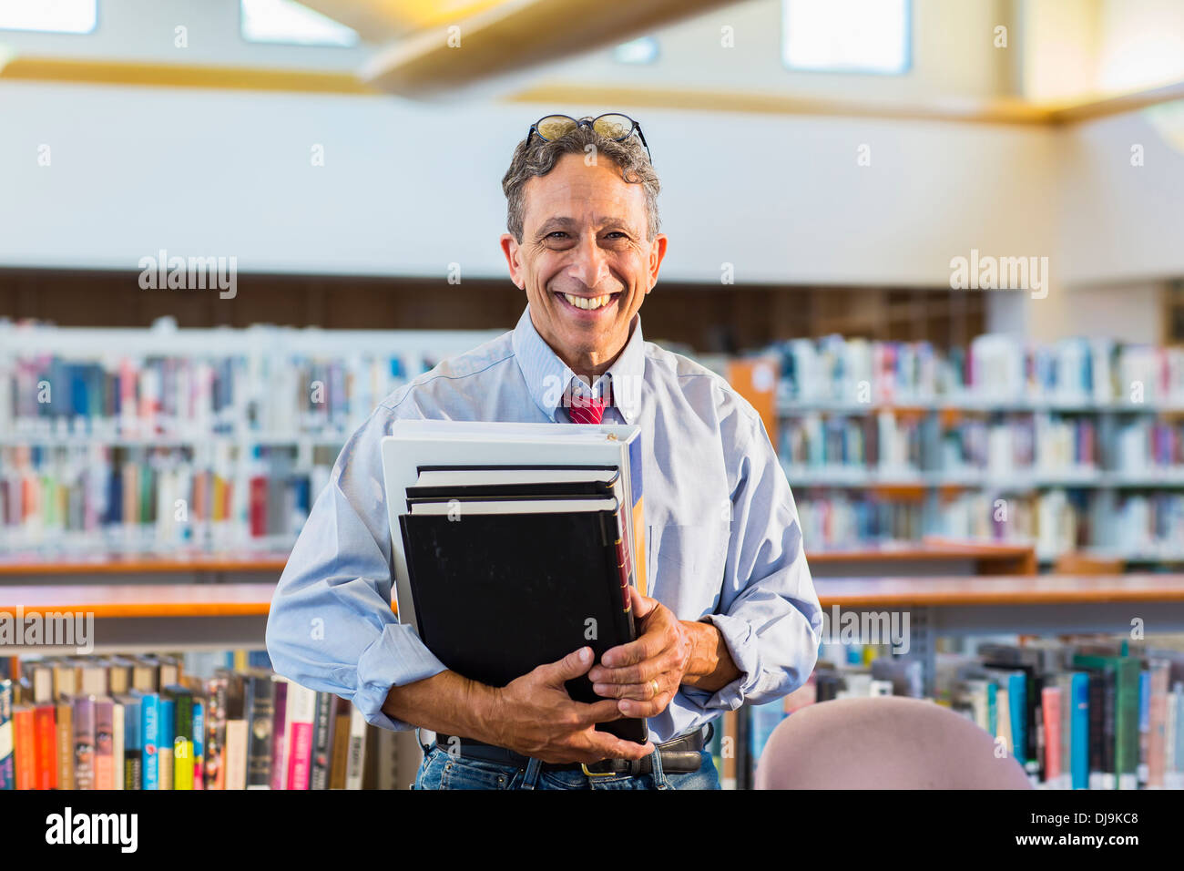 Senior man holding books in library Stock Photo - Alamy