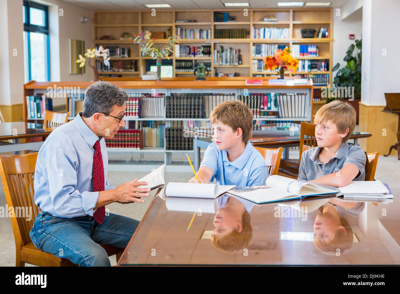 Teacher and students working in library Stock Photo - Alamy
