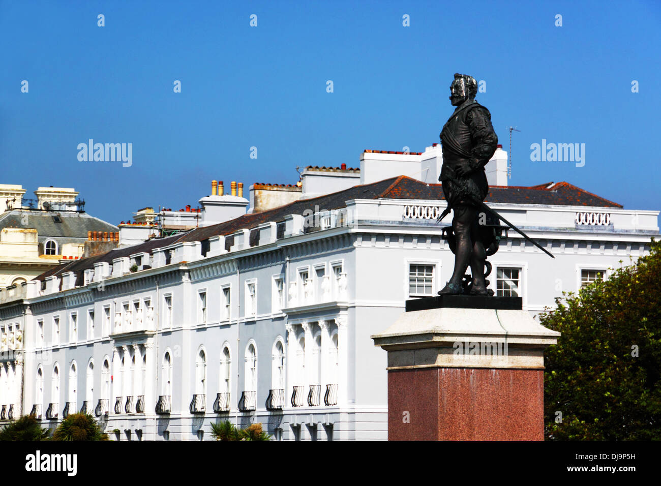 A bronze statue on a plinth with a backdrop of classical town houses ...