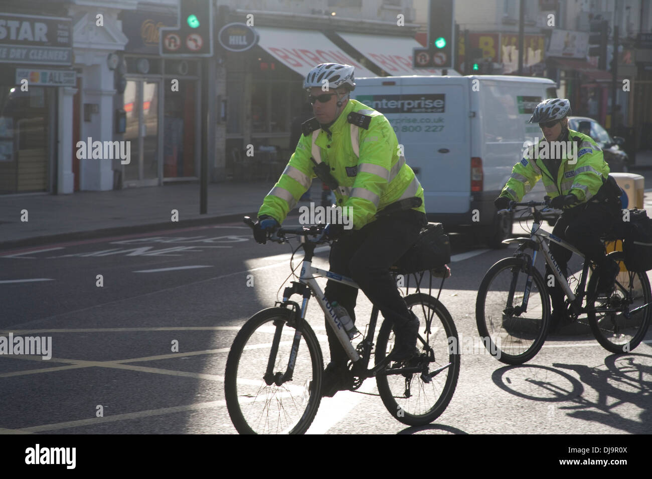 Police cyclists cycling on high street Stock Photo - Alamy