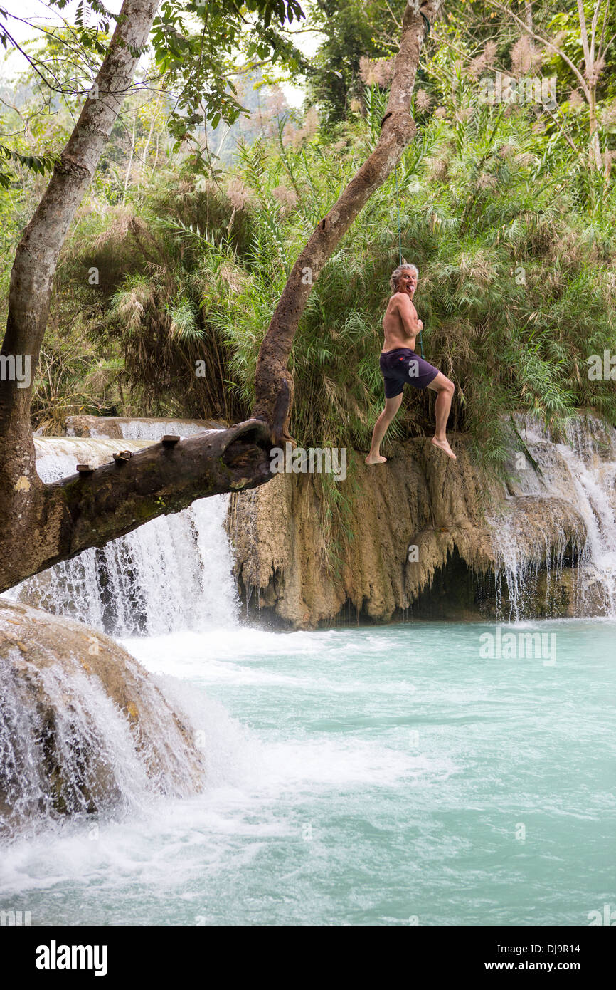 Man swinging off a tree into the Kwang Si Waterfalls near Luang Prabang ...