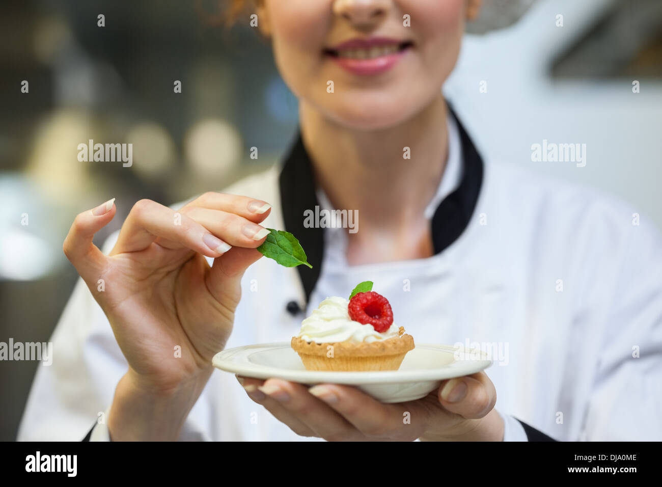 Happy head chef putting mint leaf on little cake on plate Stock Photo ...