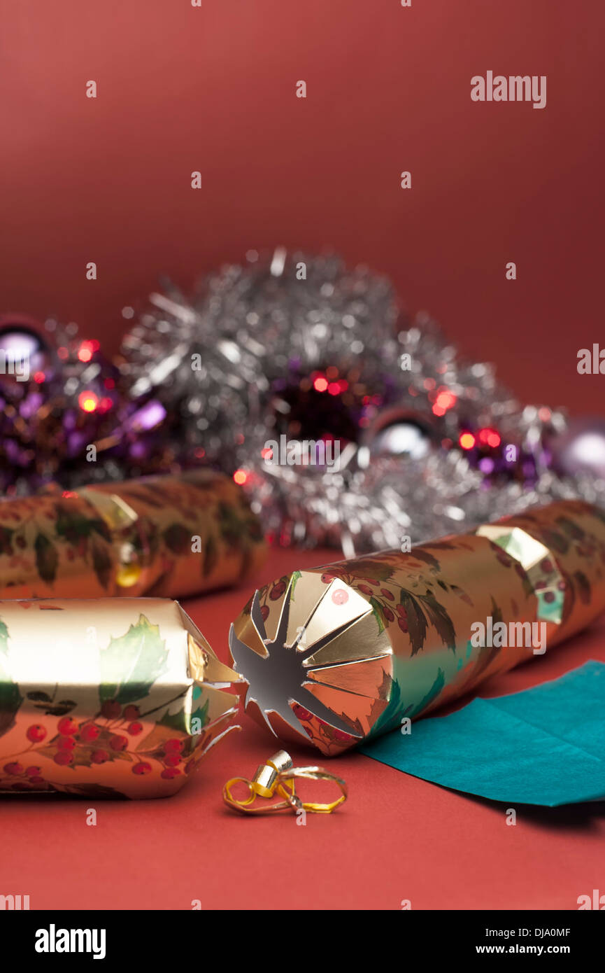 A pulled christmas cracker laying on a red background with a party hat ...
