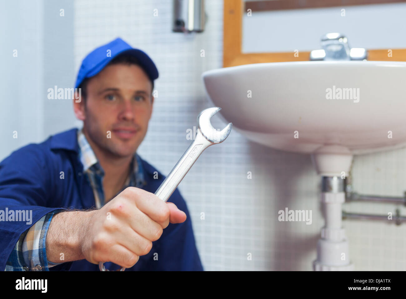Handsome smiling plumber showing wrench Stock Photo - Alamy