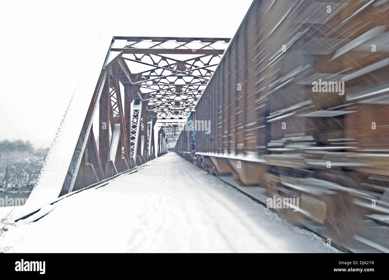 A freight train rolls over an old trestle bridge covered in snow Stock ...