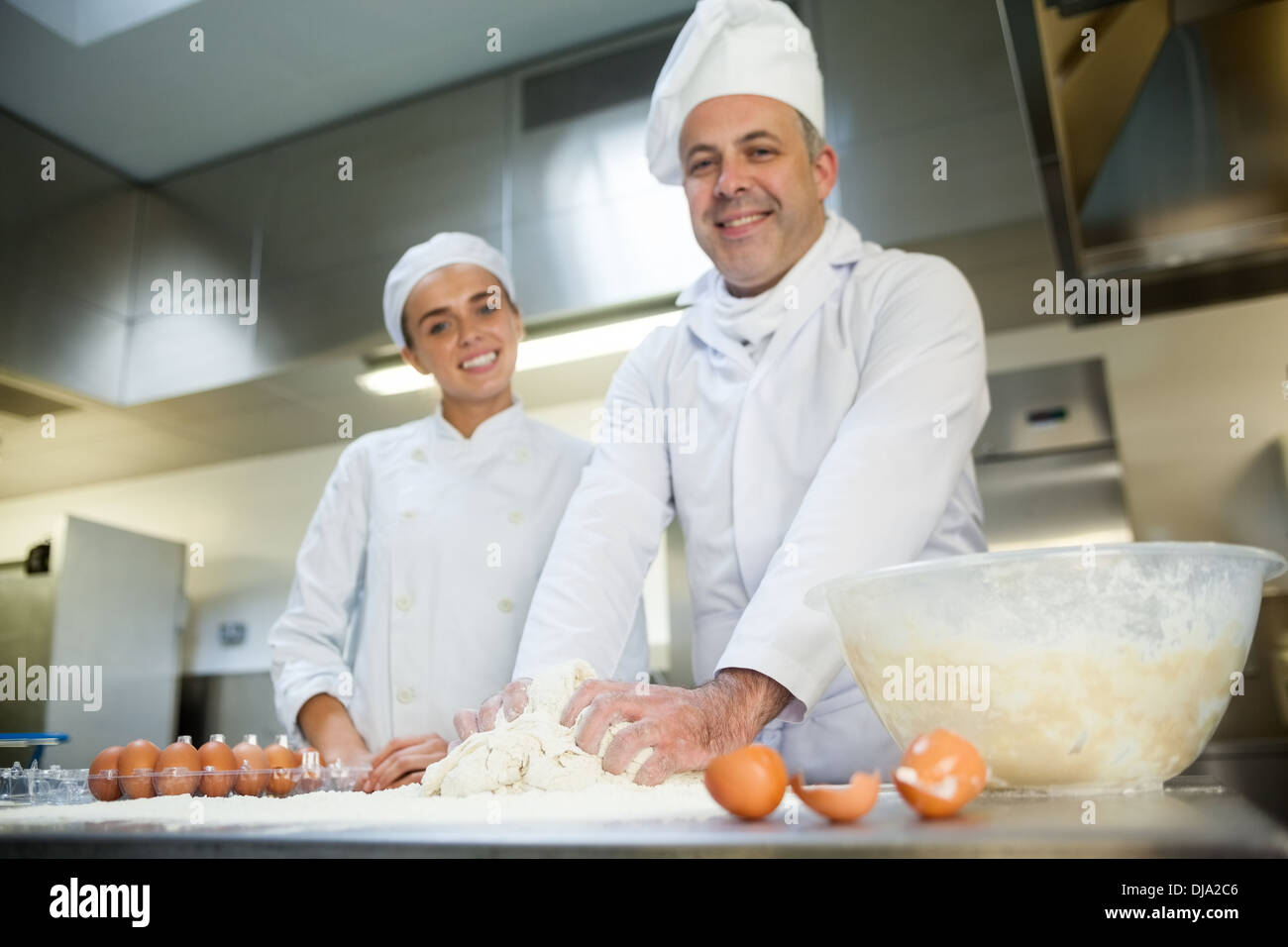 Happy head chef showing smiling trainee how to prepare dough Stock ...