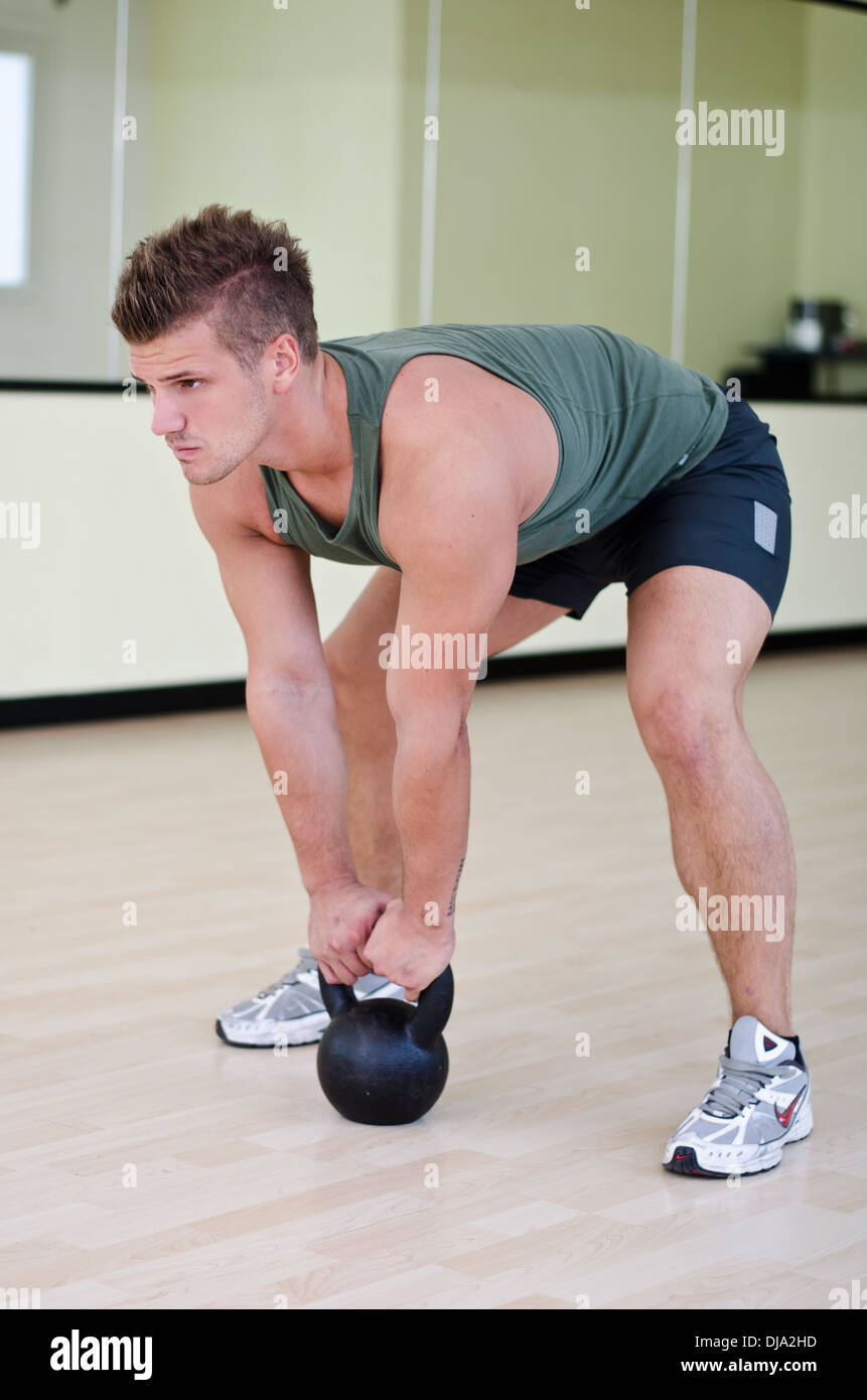 Attractive young athletic man exercising in gym, working out using ...