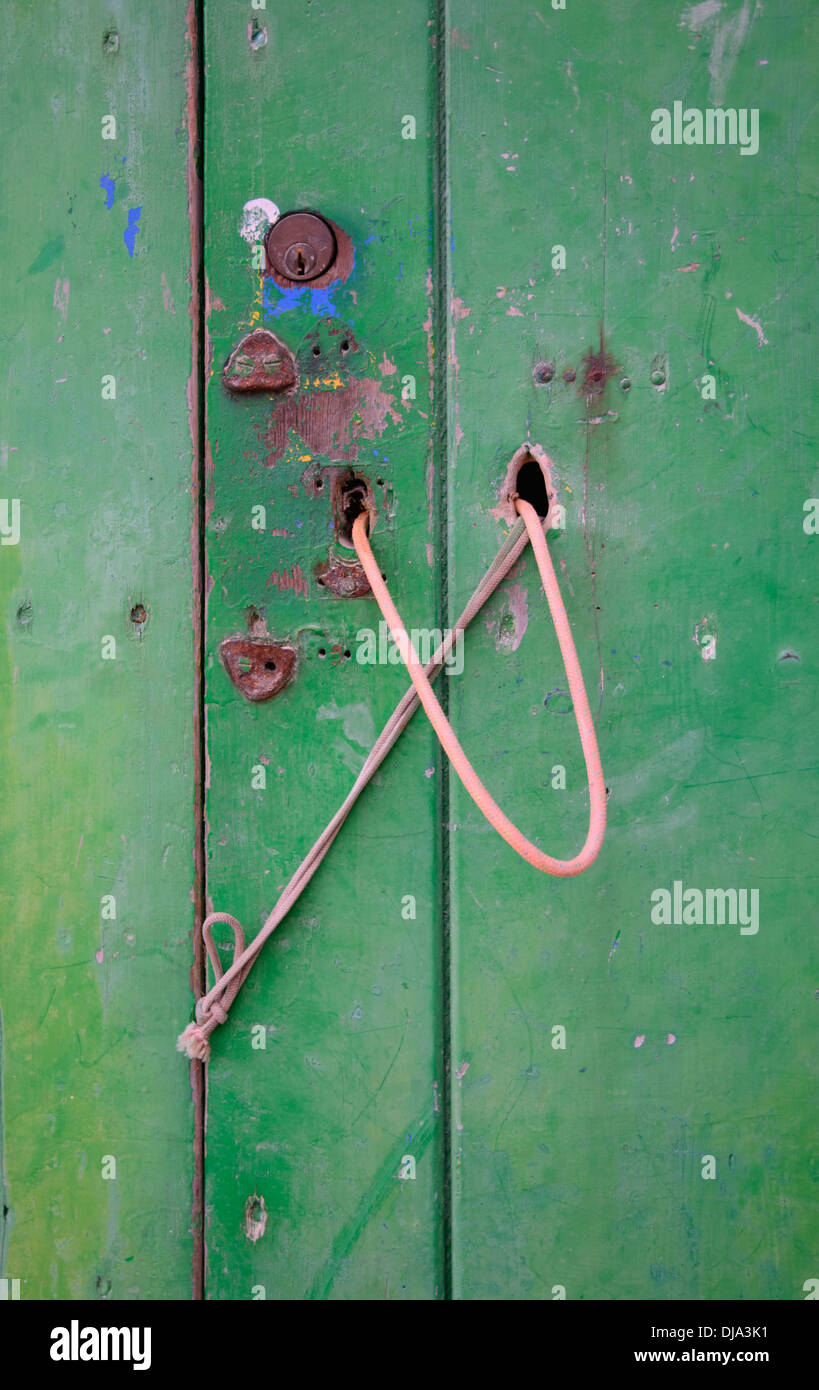Green door with rusty locks and pink string arrangement Stock Photo - Alamy
