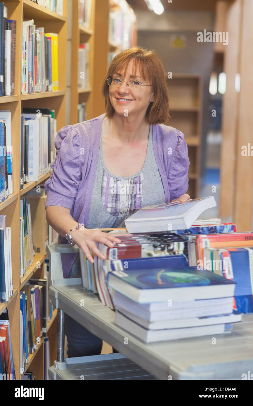 Female mature librarian returning books in library Stock Photo - Alamy