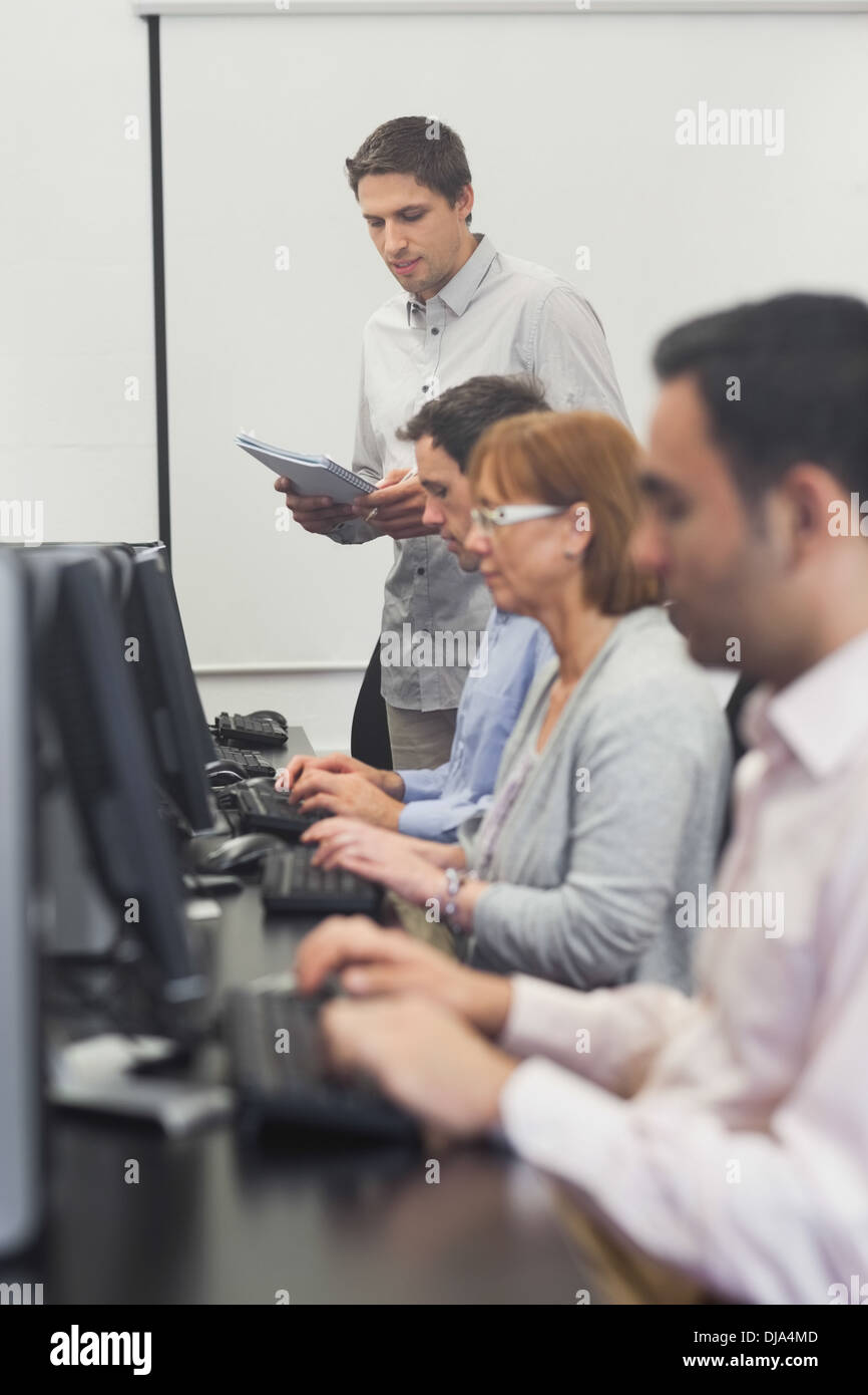 Teacher standing in front of computer class Stock Photo - Alamy