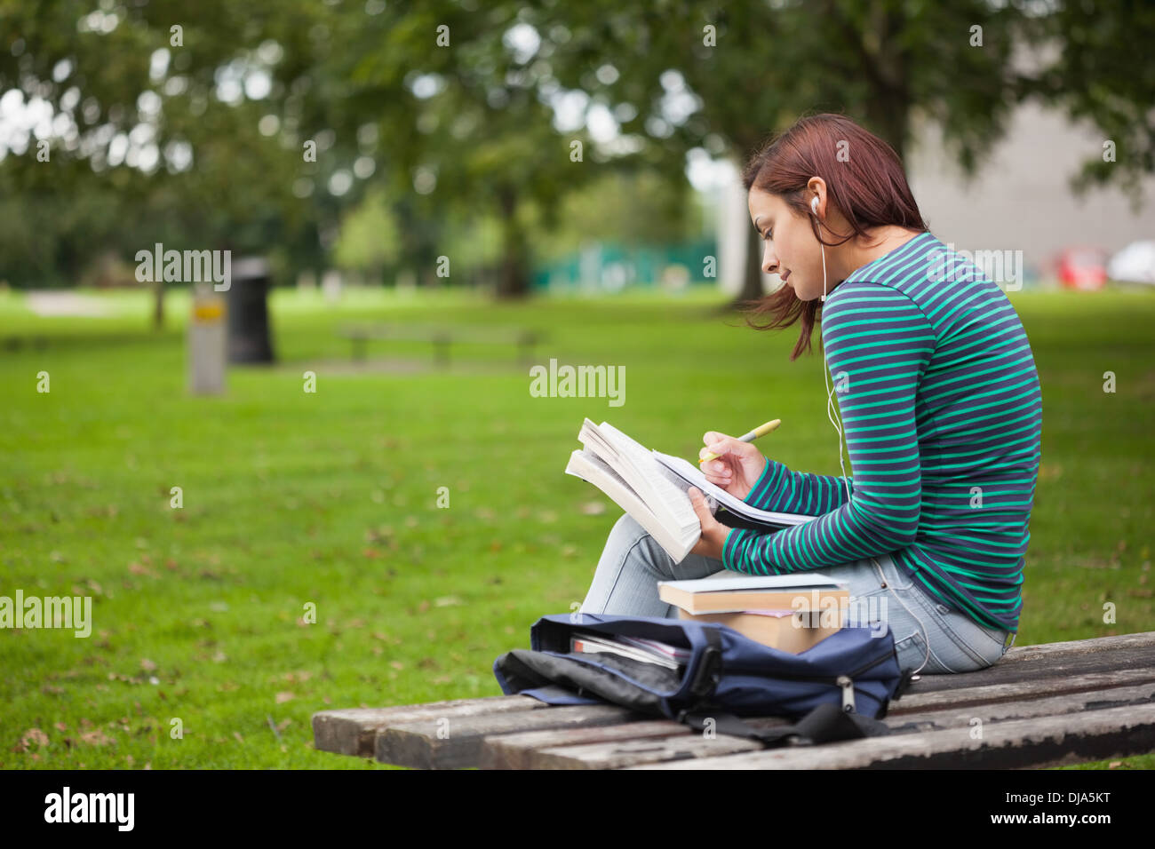 Serious casual student sitting on bench taking notes Stock Photo - Alamy