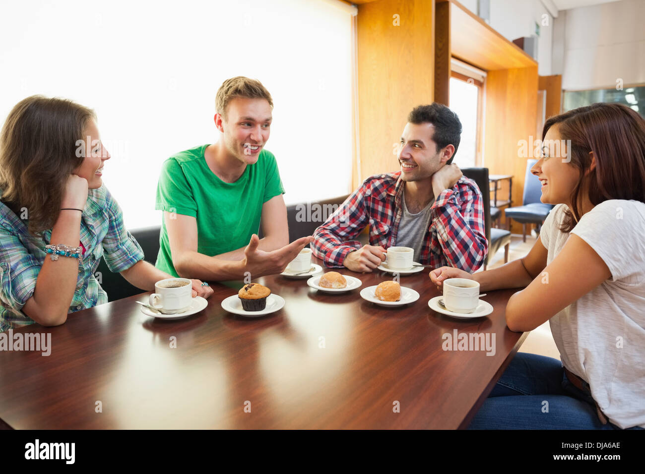 Four happy students having a cup of coffee chatting in college canteen ...