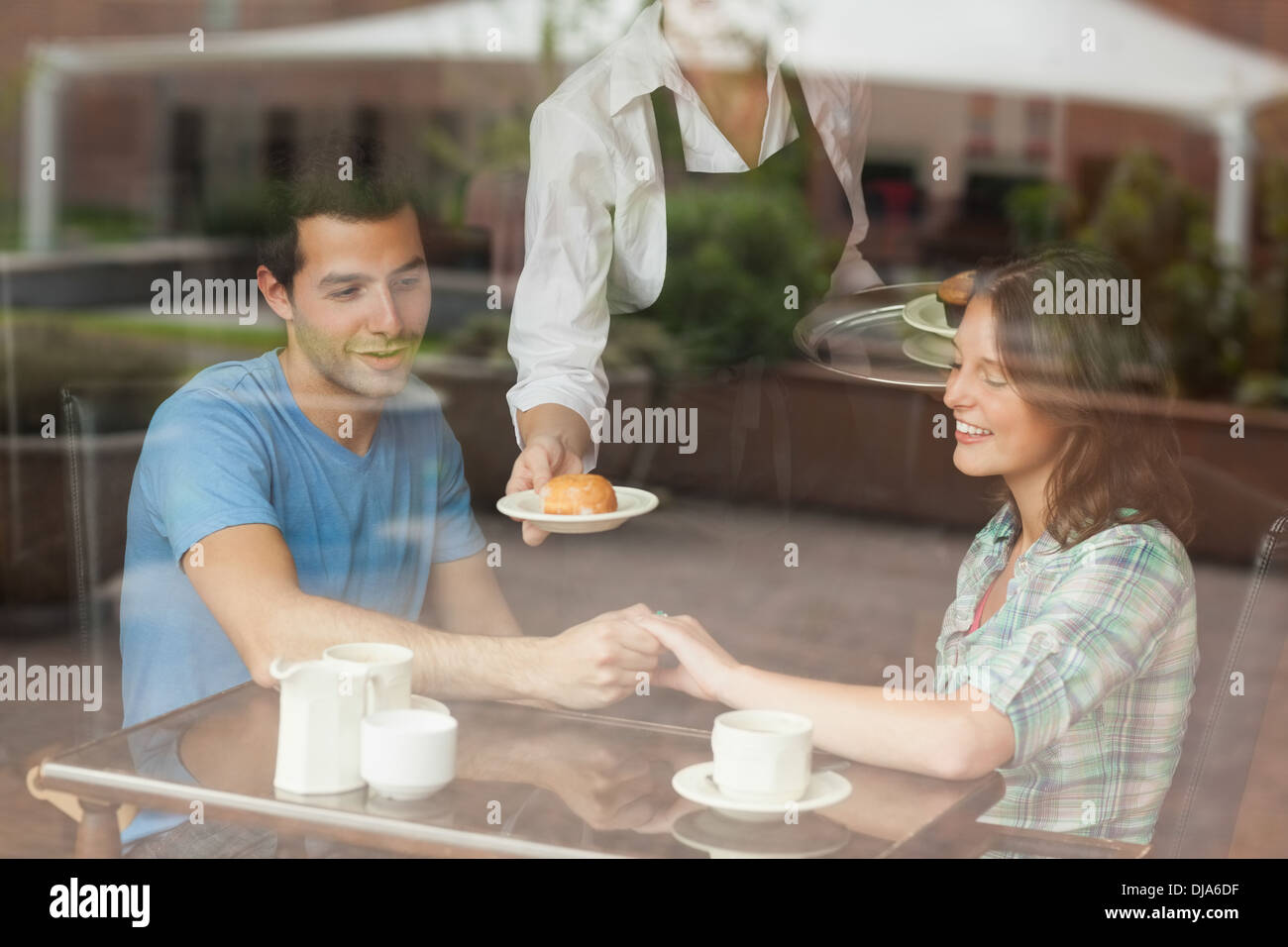 A couple holding hands while waitress serving food Stock Photo - Alamy