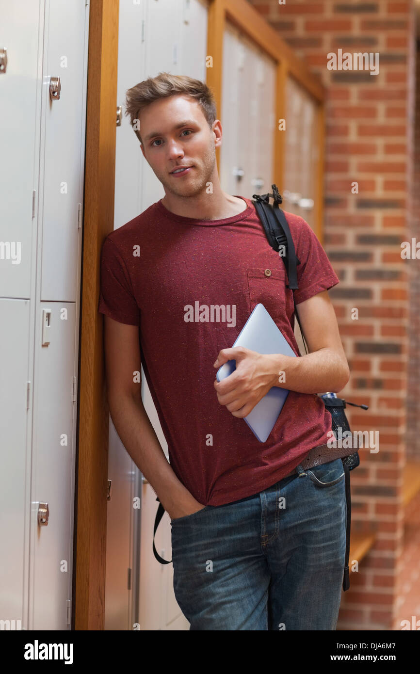 Handsome student leaning against lockers using tablet in school Stock ...