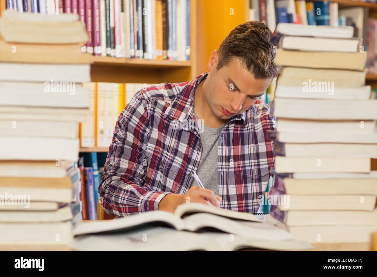 Focused handsome student studying between piles of books Stock Photo ...