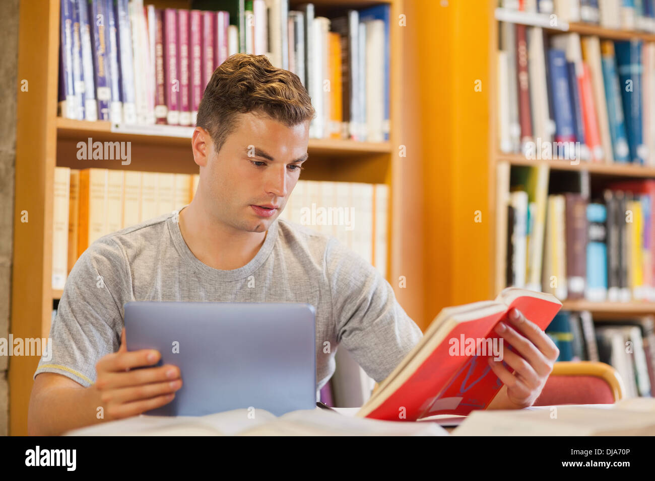 Attractive smiling student using tablet and holding book Stock Photo ...