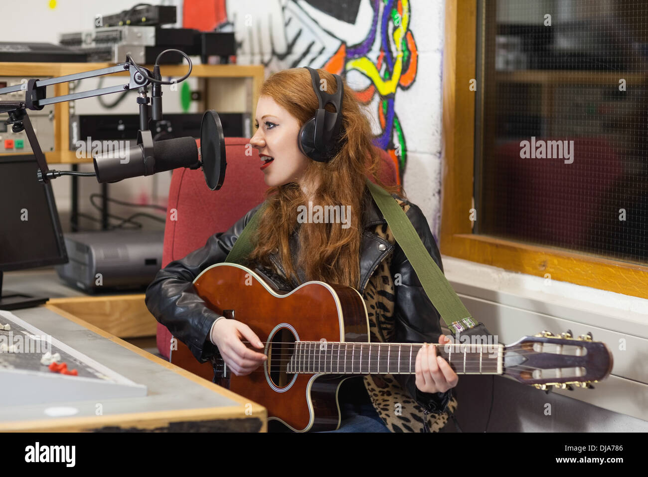 Happy beautiful singer recording and playing guitar Stock Photo - Alamy