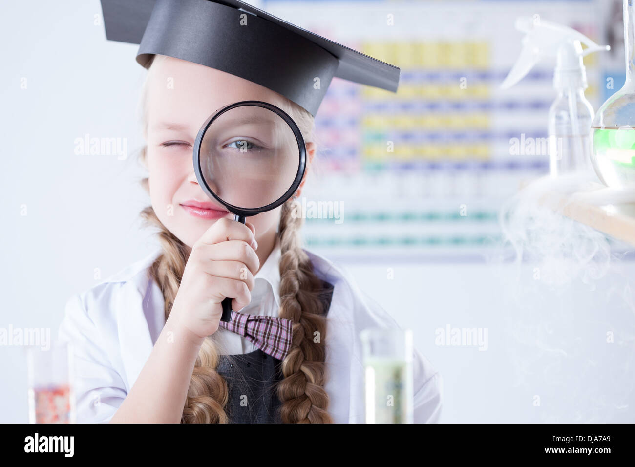 Smiling schoolgirl looks through magnifying glass Stock Photo - Alamy