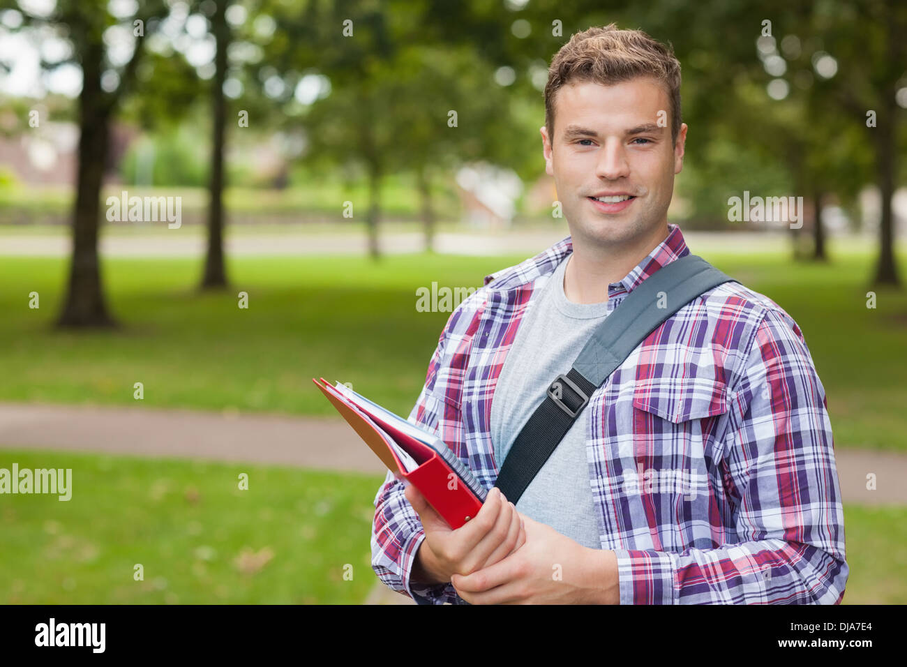 Handsome smiling student carrying folder Stock Photo - Alamy