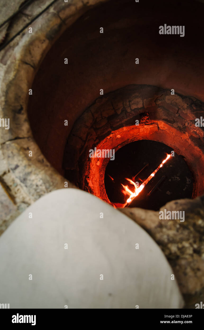 Traditional Arab flatbread being prepared in a fire pit at a restaurant ...