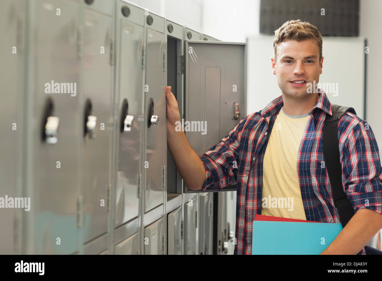 Smiling handsome student standing next to locker Stock Photo - Alamy